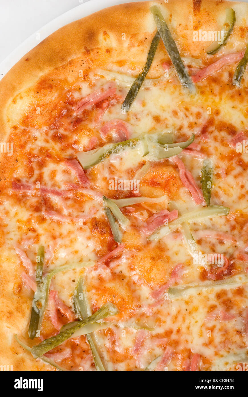 pizza closeup with boiled sausage, ham, marinated gherkin and ...