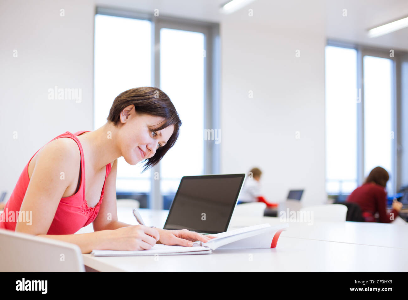 Pretty young college student studying in the library/a study room at ...