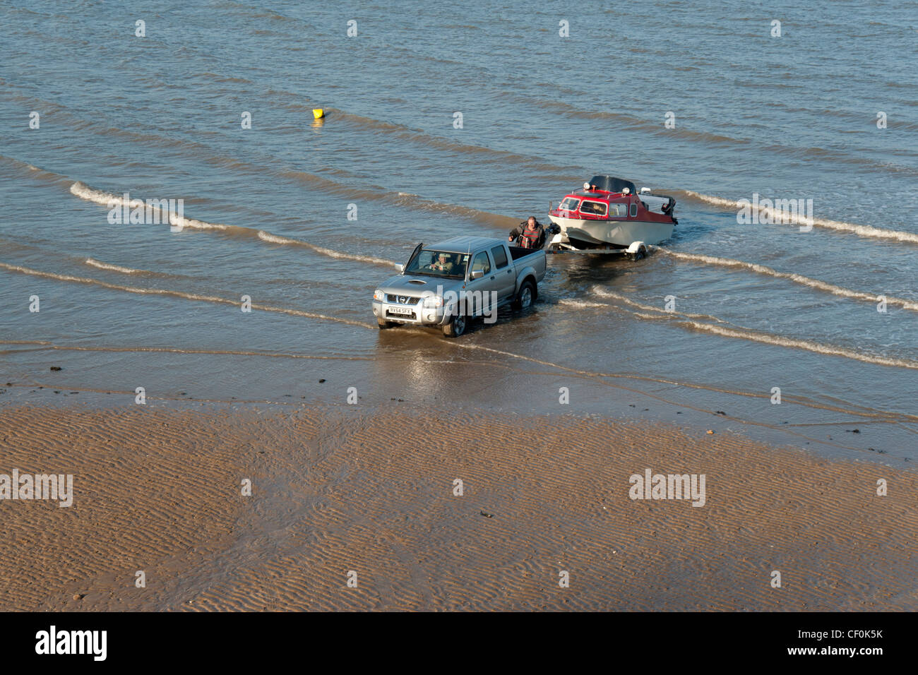 A 4x4 bringing in a boat as the tide comes in at The Mumbles, Wales ...