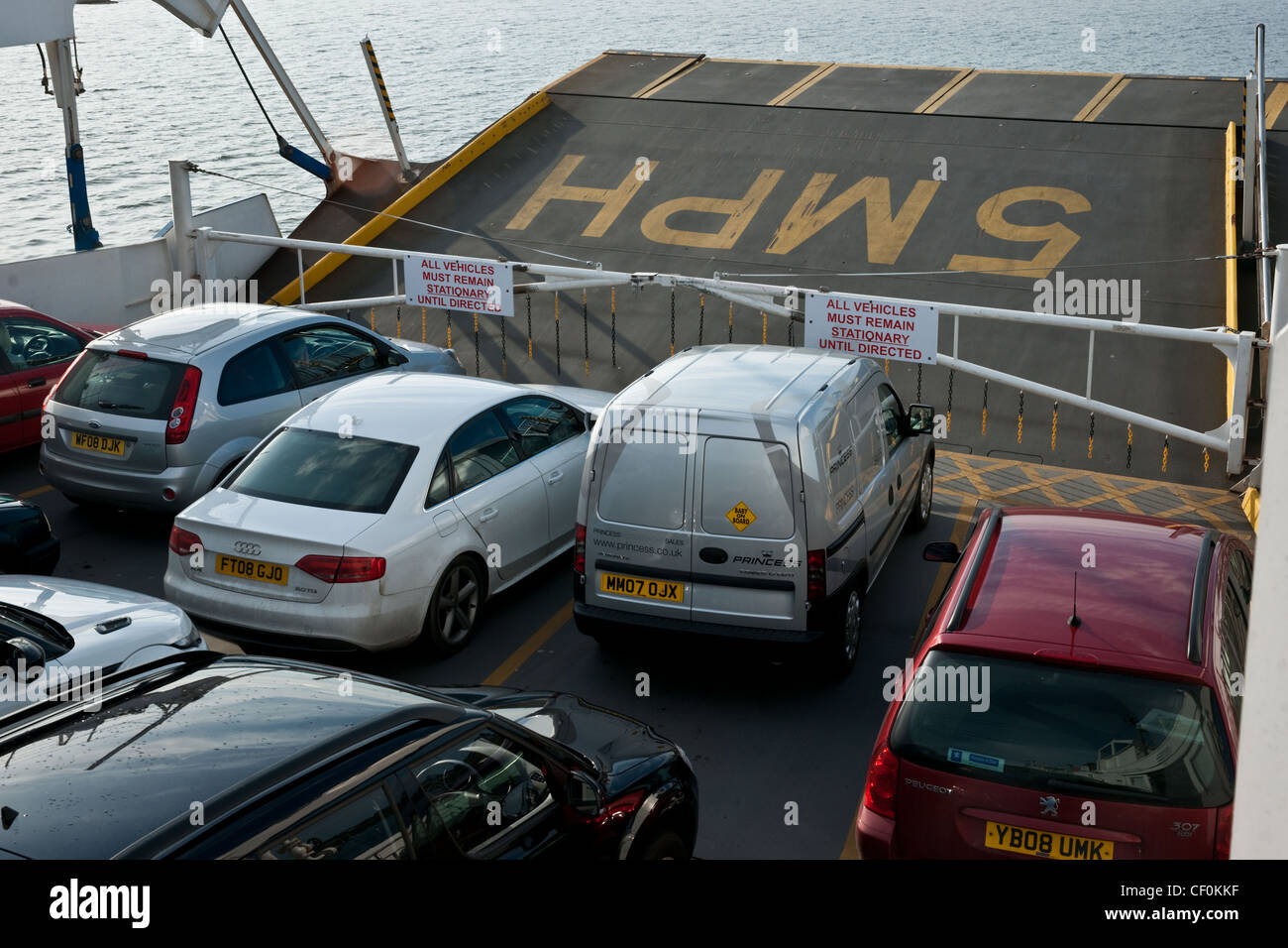 Cars on a small car ferry crossing a river. The barriers are closed and ...