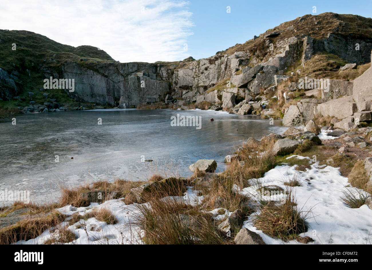 Snow and ice around frozen water in Foggin Tor disused quarry, Dartmoor ...