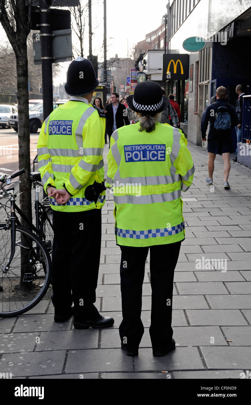 Metropolitan Police Officers, male and female seen from behind on ...