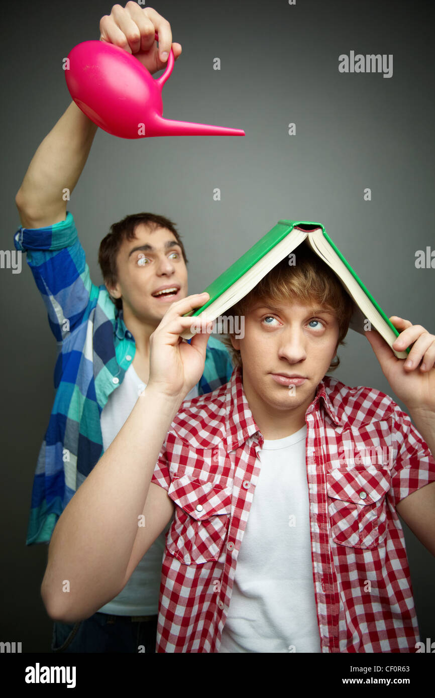 Freaky guy pouring water over his friend hiding under a book, fool’s ...