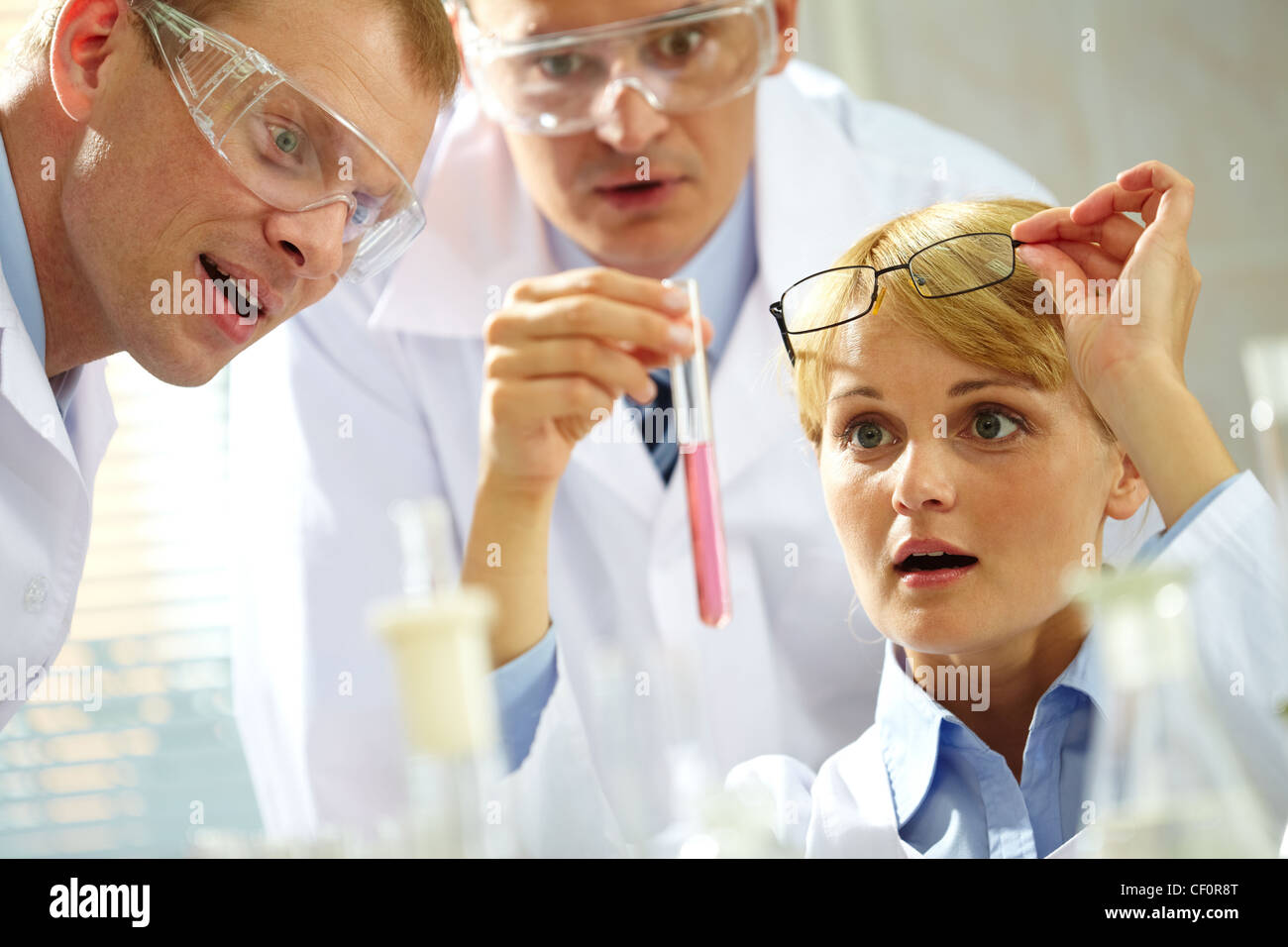 Three inspired scientists looking at a substance discovered in a lab ...