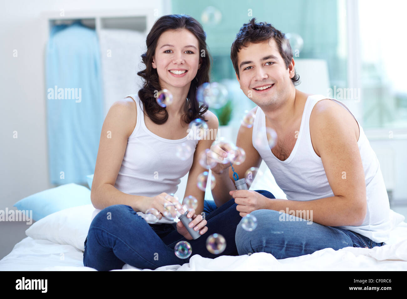 Cheerful couple blowing bubbles at home and smiling Stock Photo - Alamy