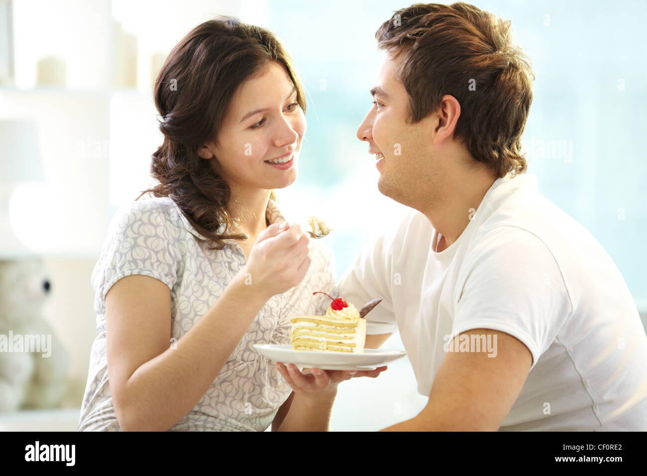 Loving couple eating cake together Stock Photo - Alamy