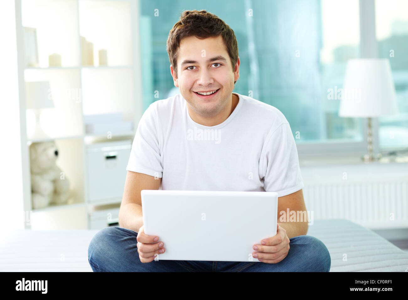 Smiling guy with laptop looking at camera Stock Photo - Alamy