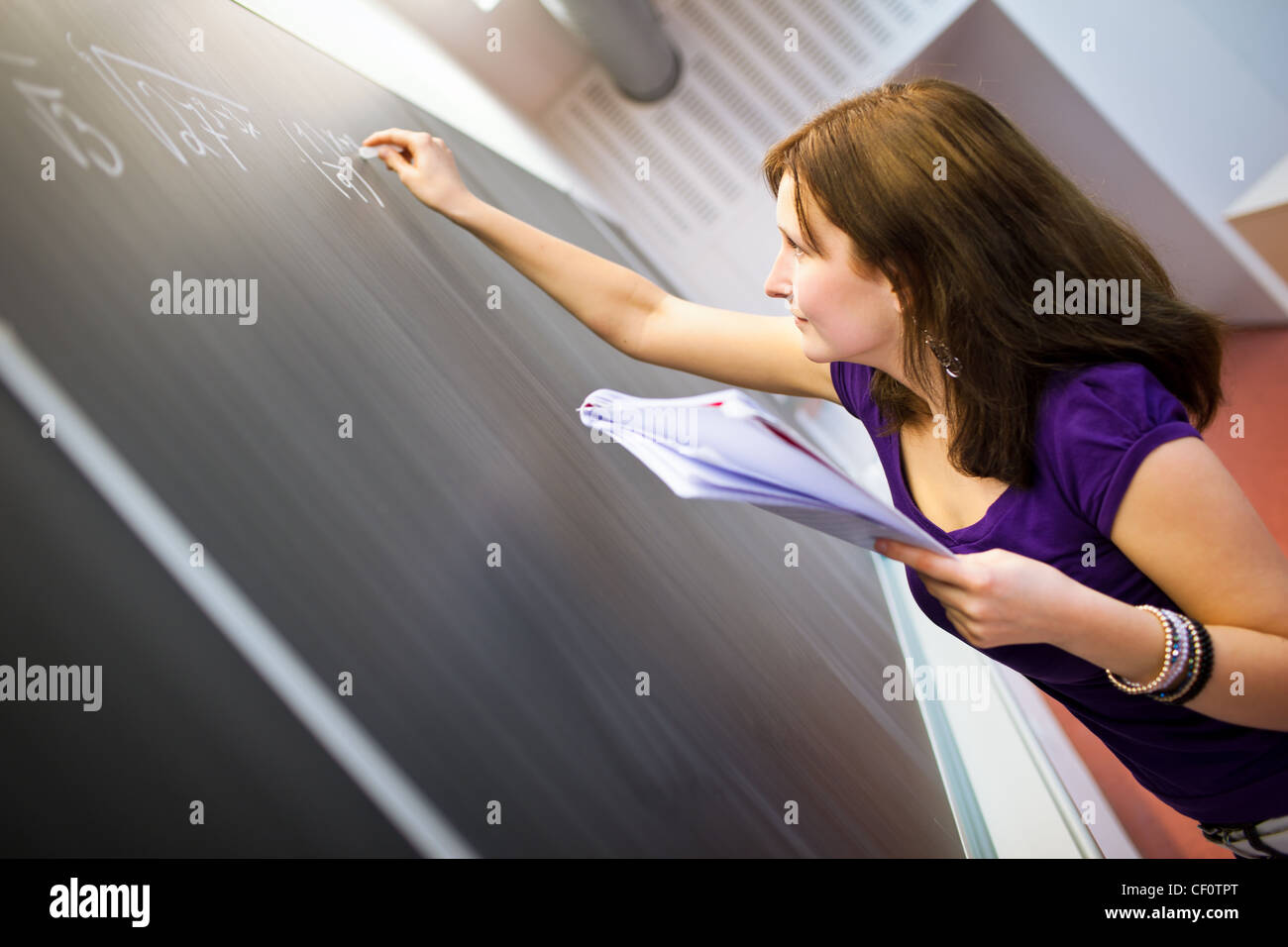 pretty young college student writing on the chalkboard/blackboard ...