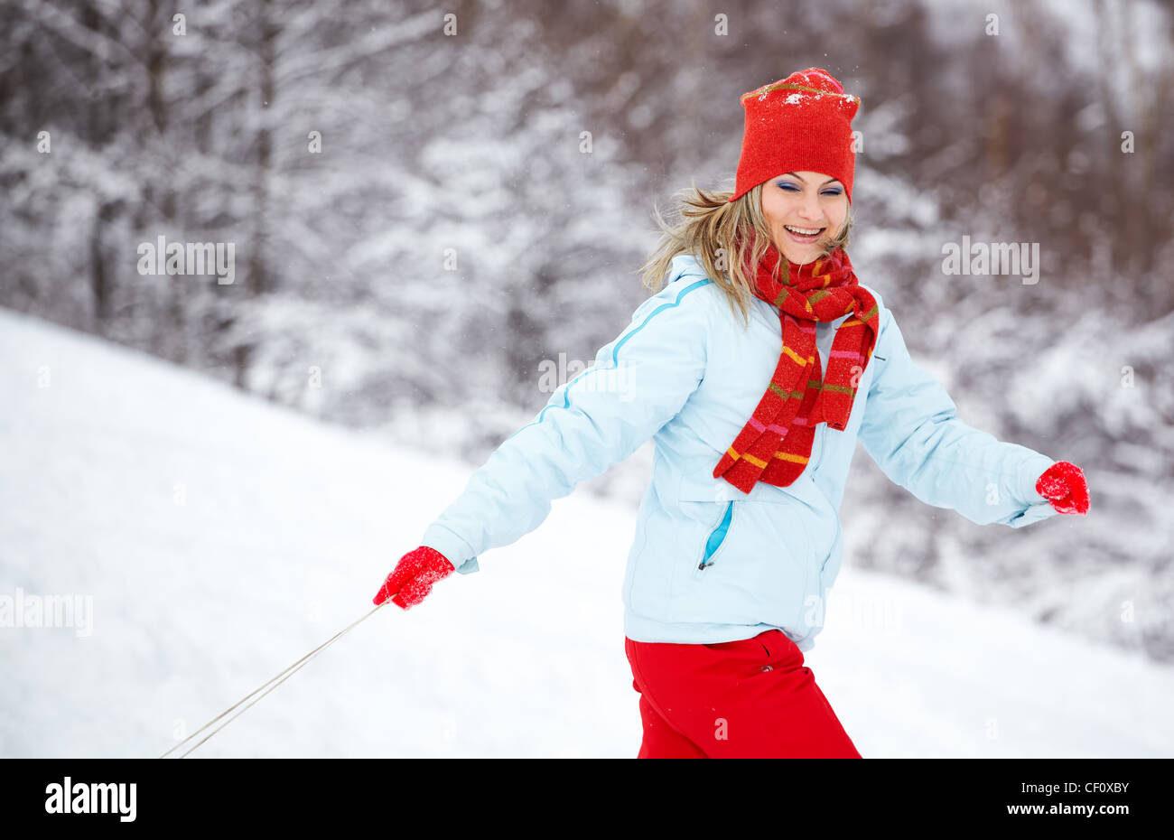 Young woman running through the snow, pulling a slay and smiling Stock ...