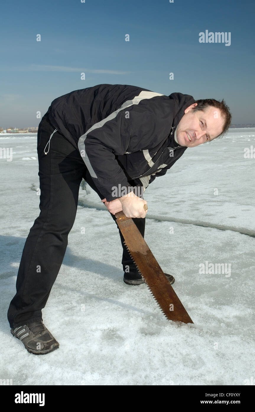 Man sawing with a hand saw a diving hole. Preparations for subglacial ...