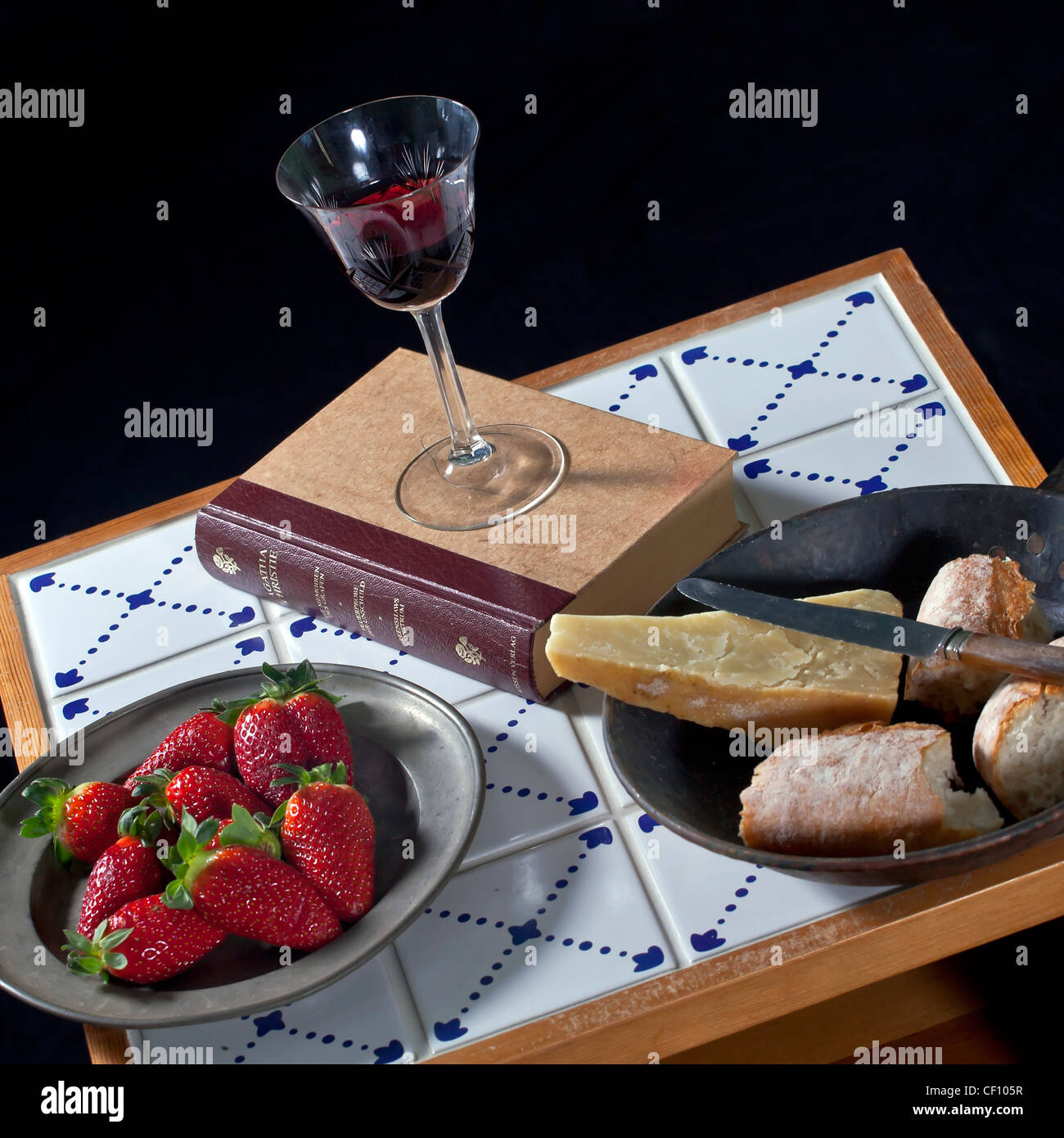 cozy snack: a book on a table made of old tiles with red wine ...