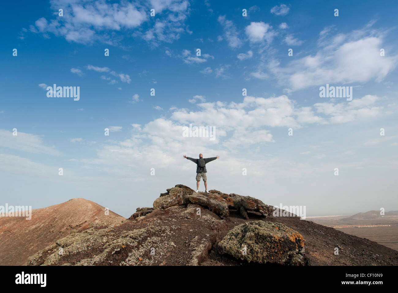 man standing on top of a volcano arms stretched out Stock Photo - Alamy