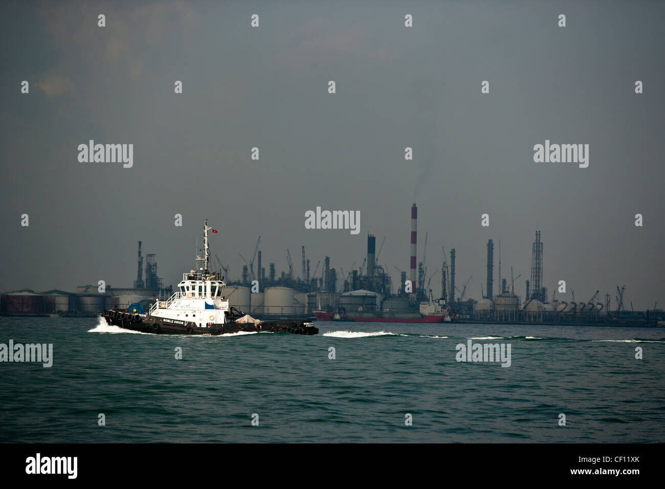 A tug boat passes in front of an offshore oil refinery in Singapore ...