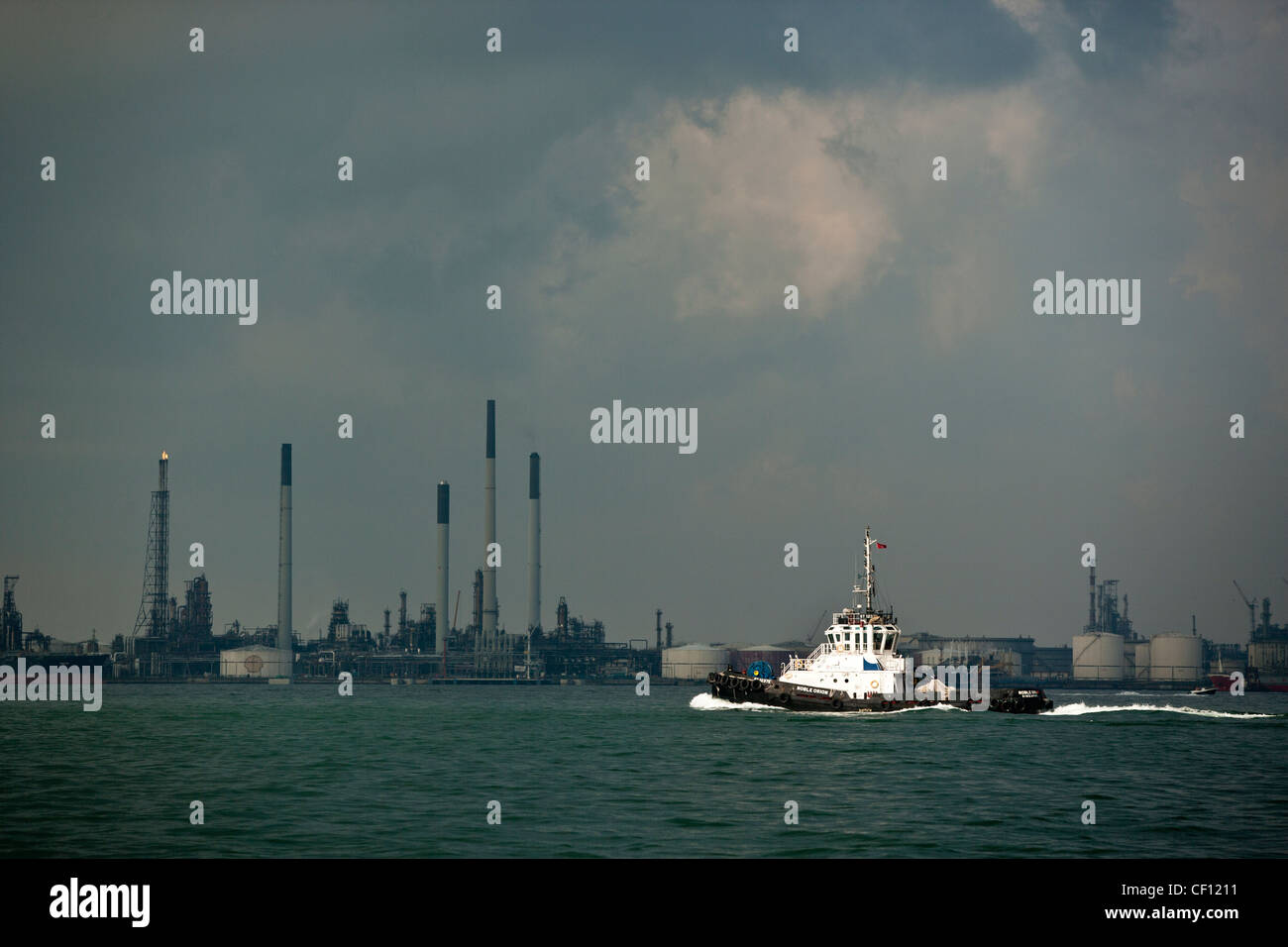 A tug boat passes in front of an offshore oil refinery in Singapore ...