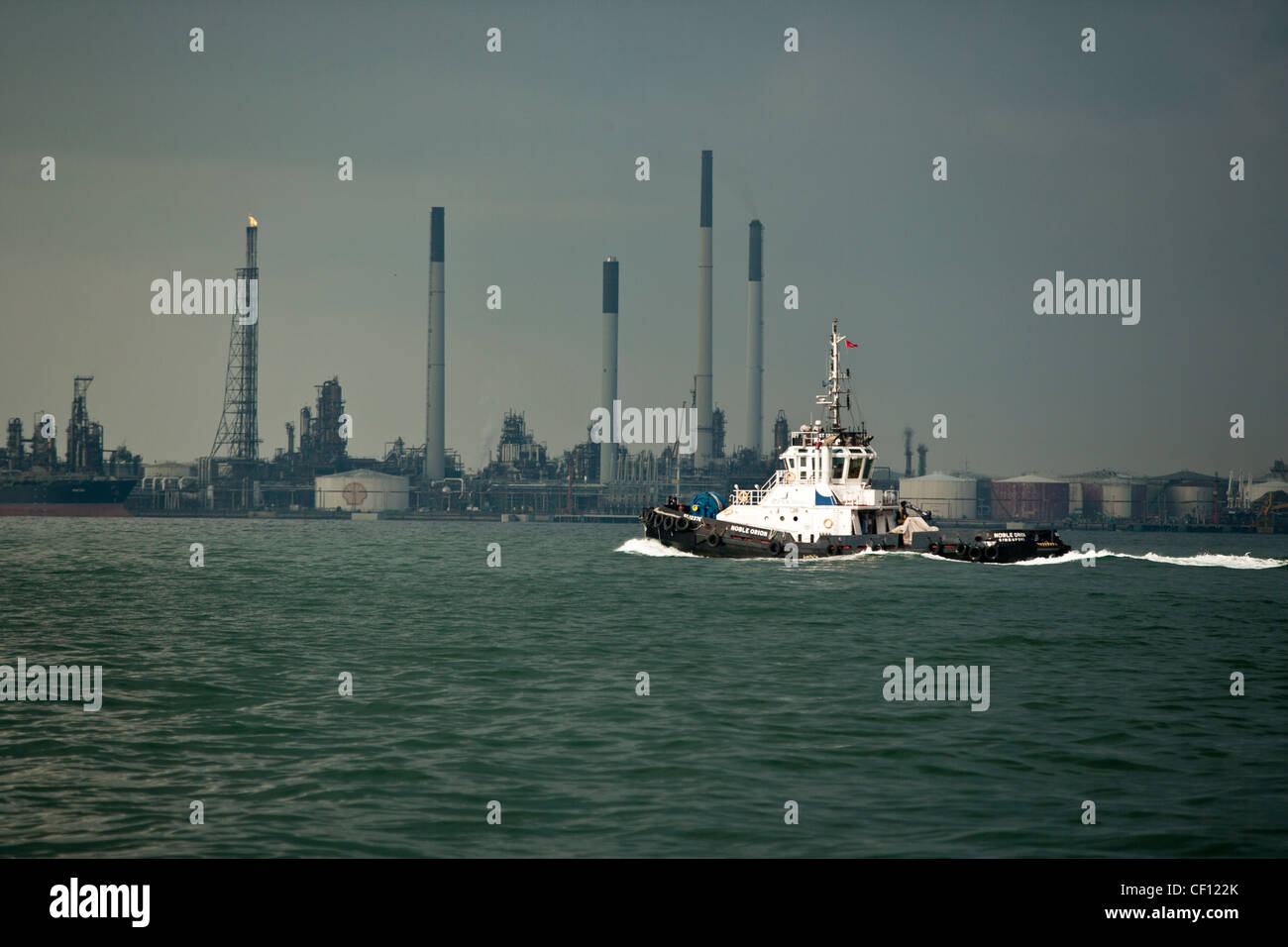 A tug boat passes in front of an offshore oil refinery in Singapore ...