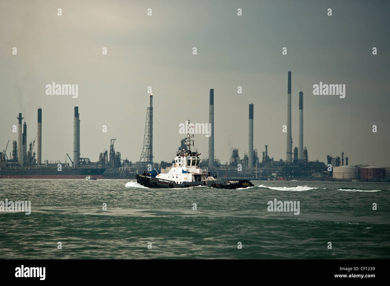 A tug boat passes in front of an offshore oil refinery in Singapore ...