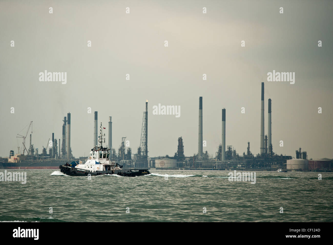A tug boat passes in front of an offshore oil refinery in Singapore ...
