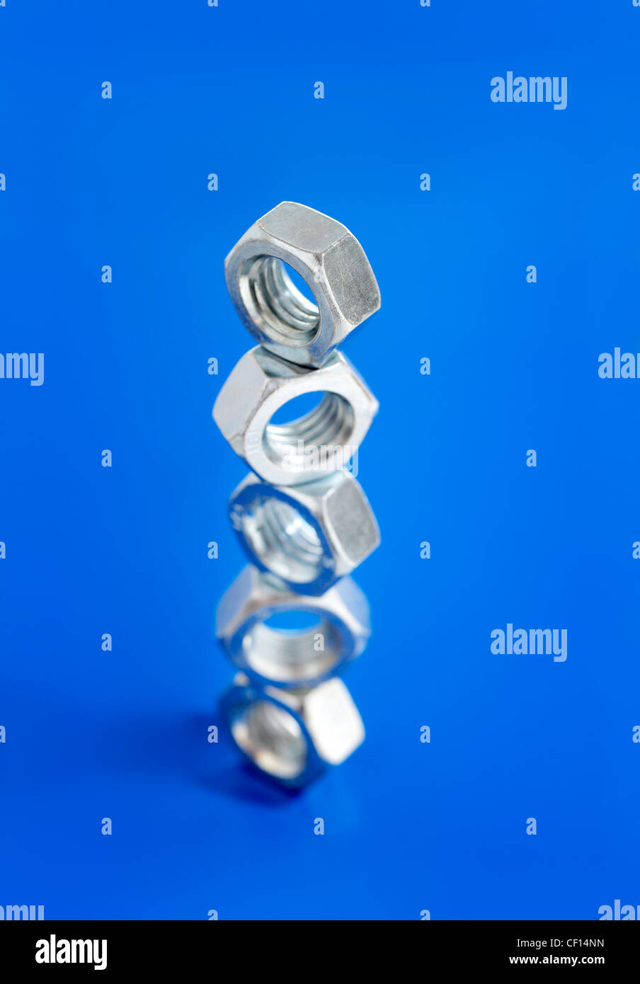 Steel nuts stacked on blue background Stock Photo - Alamy