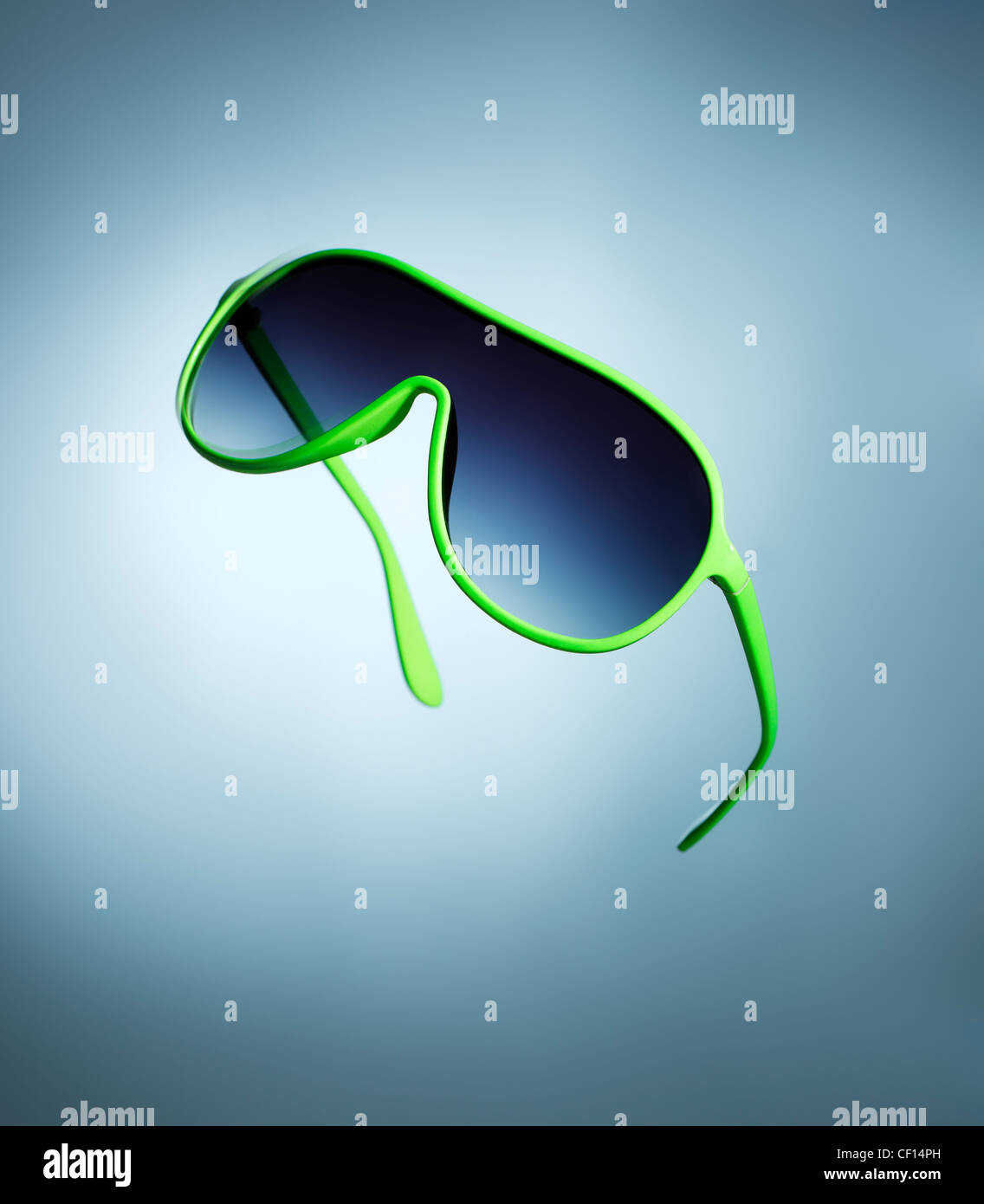 Cheap green 1980s style plastic sunglasses on blue background Stock ...