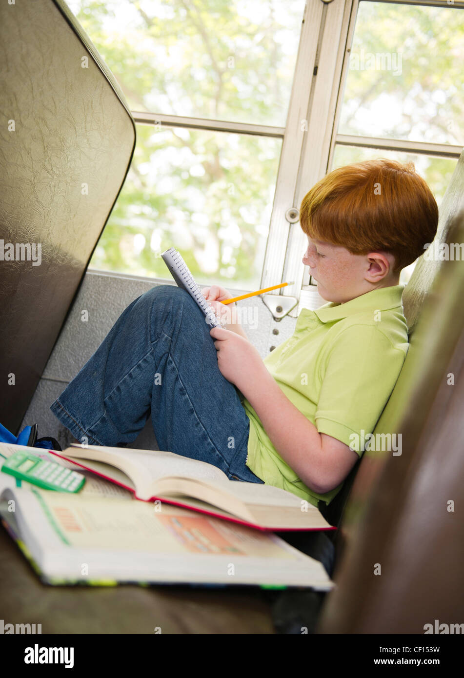 Caucasian boy doing homework on school bus Stock Photo - Alamy