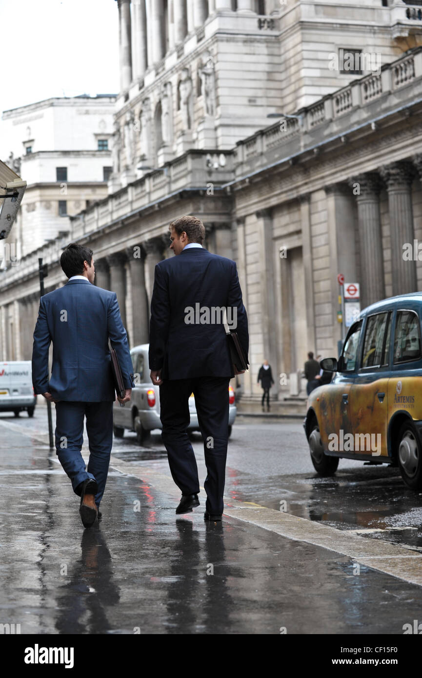 Two City of London bankers chat as they walk past The Bank of England ...