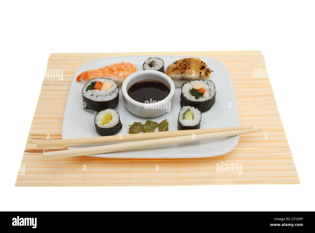 Group of mixed sushi on a plate upon a bamboo matt with chopsticks ...