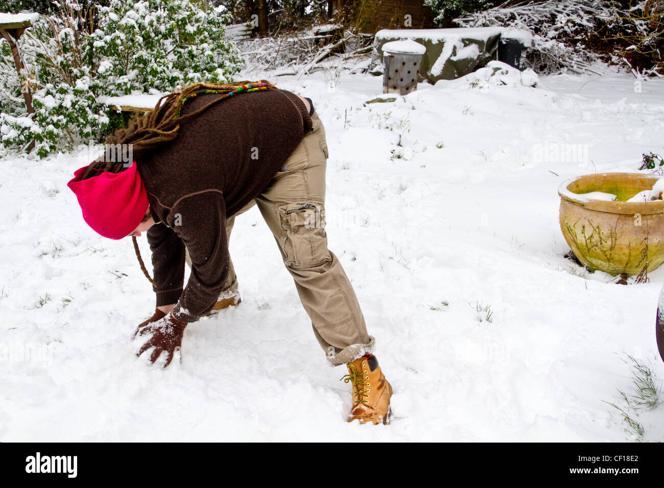 Young Caucasian man with dreadlocks scooping up snow Stock Photo - Alamy