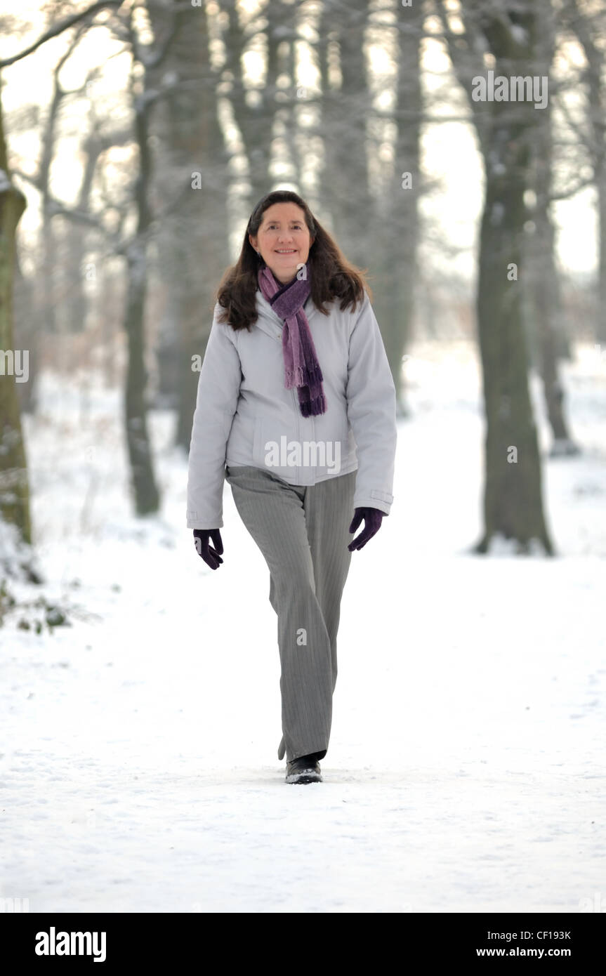 Middle aged woman walking in the snow Stock Photo - Alamy