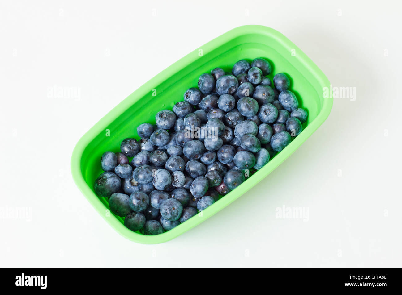 Freshly washed blueberries in a green bowl photographed on a white ...