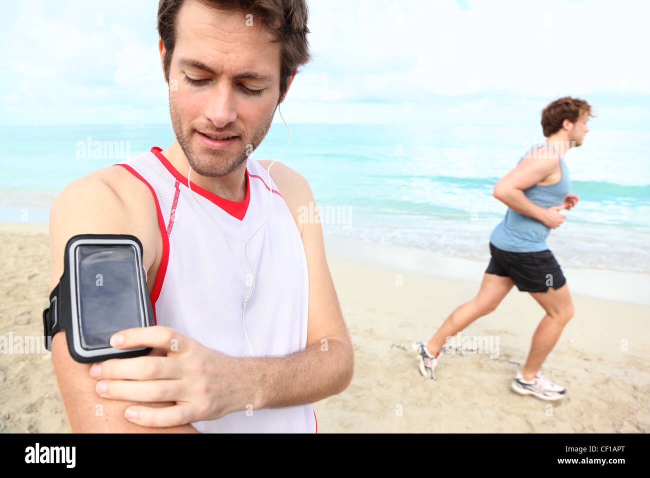 Running workout man with mp3 music player listening to music with mp3 ...