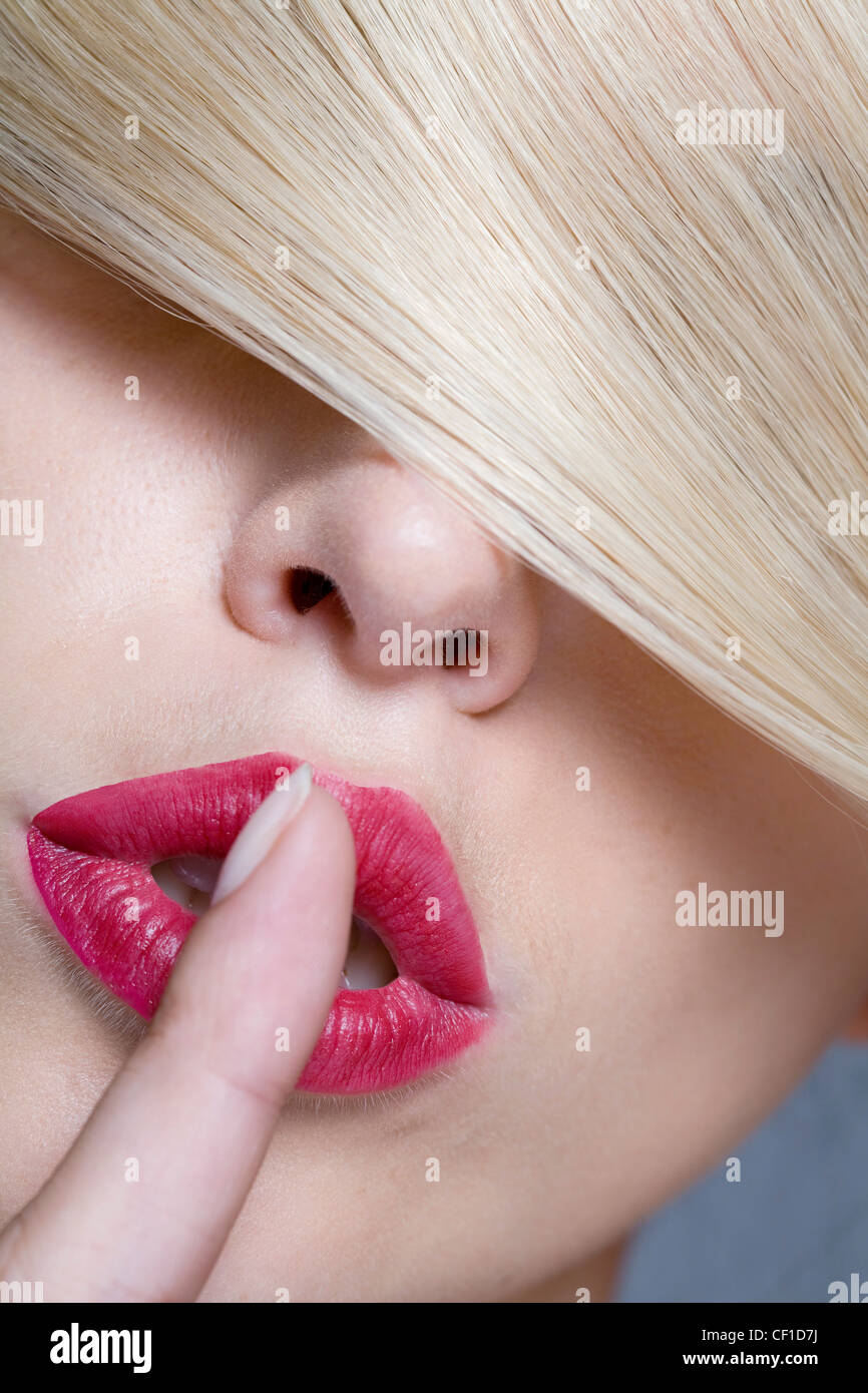 Female with deep pink lips and blonde hair sweeping across her eyes ...