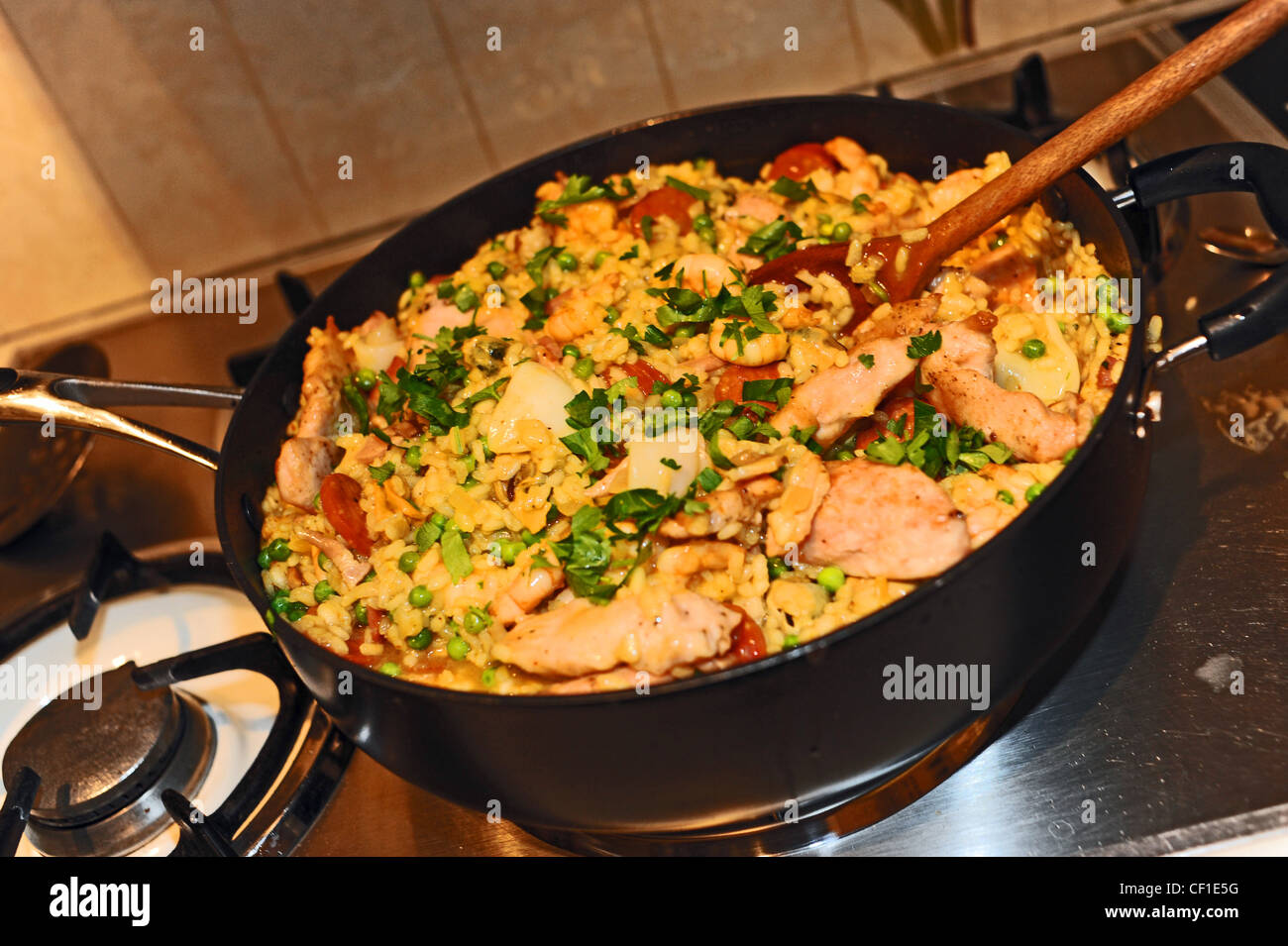 Pan of Paella a traditional Spanish dish cooking with wooden spoon ...
