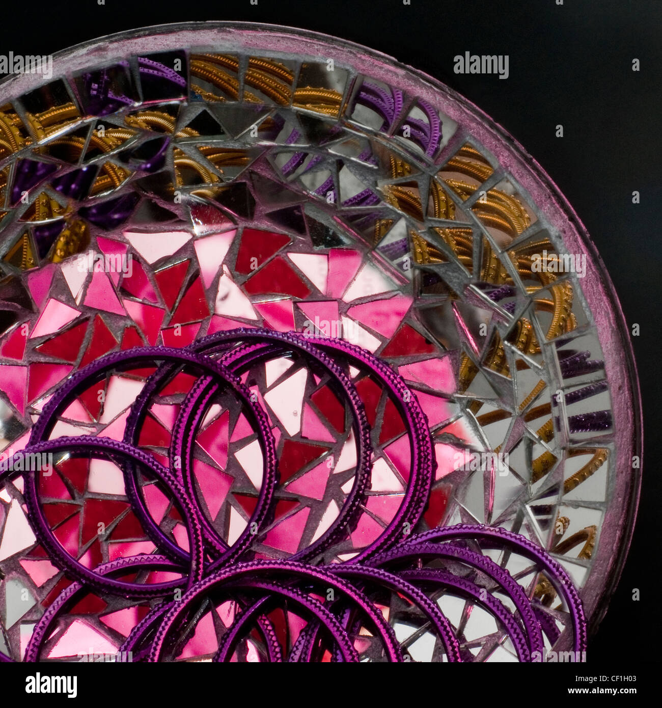 Bangles lying on and reflected in a mirrored plate Stock Photo - Alamy