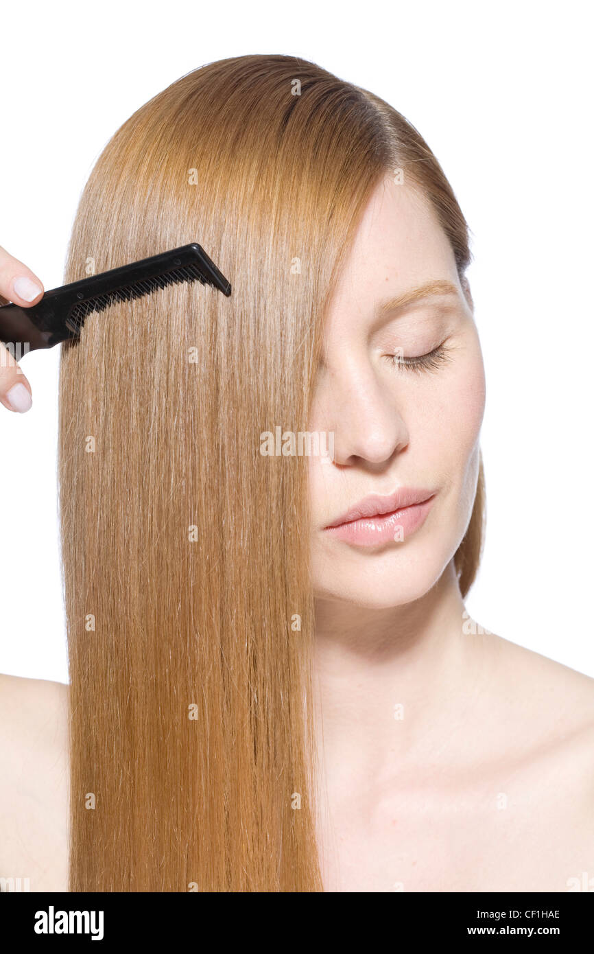 Female combing long straight fair hair with black plastic hair comb ...