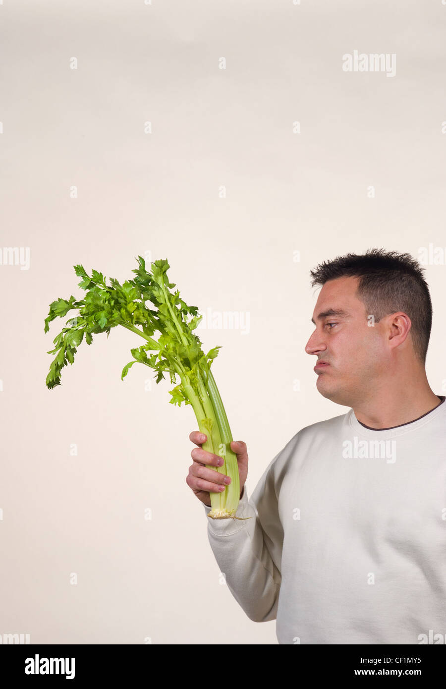 Guy holding a bunch of celery, diet frustration concept Stock Photo - Alamy