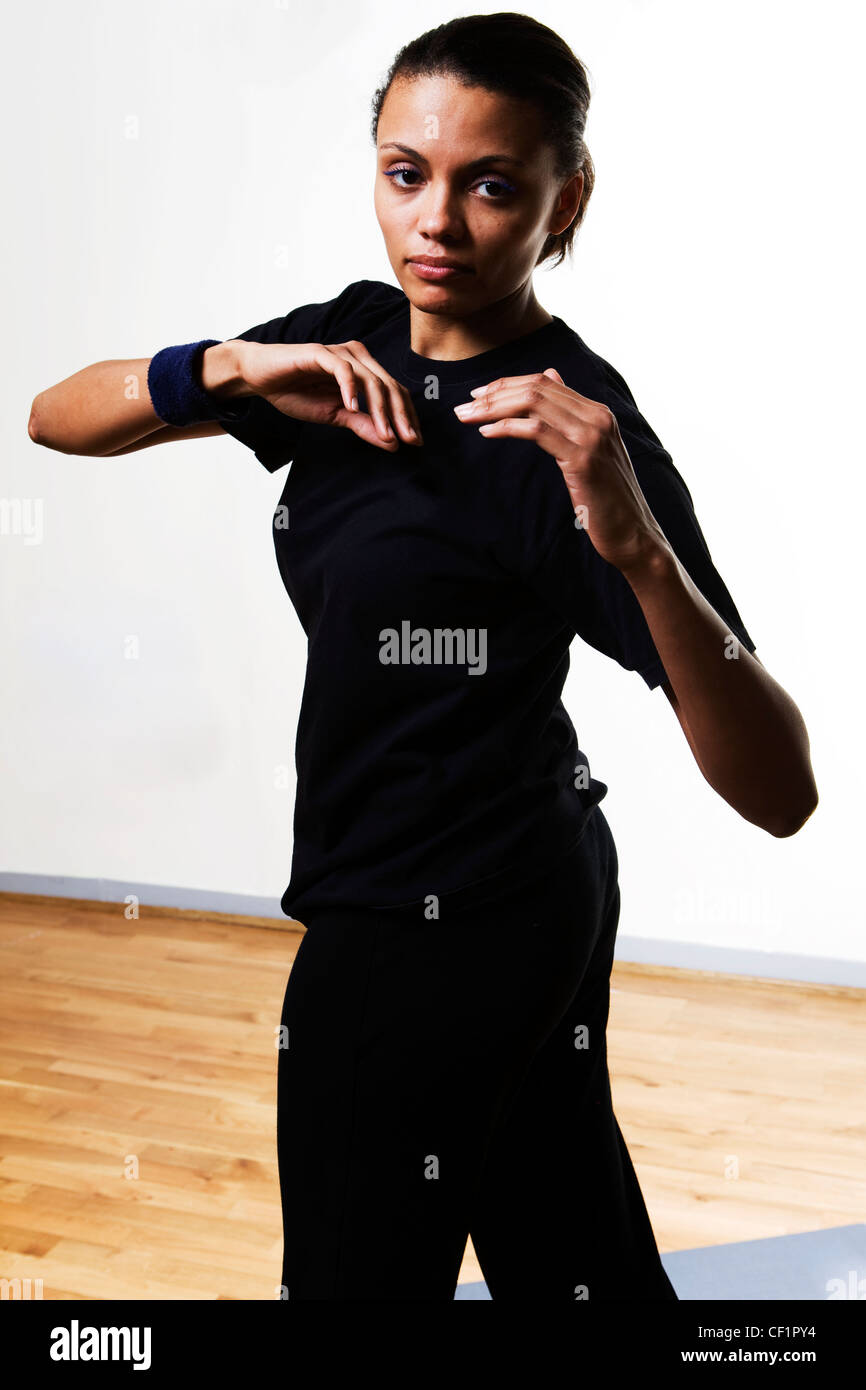 A young woman stretching inside a studio before a martial arts fight ...