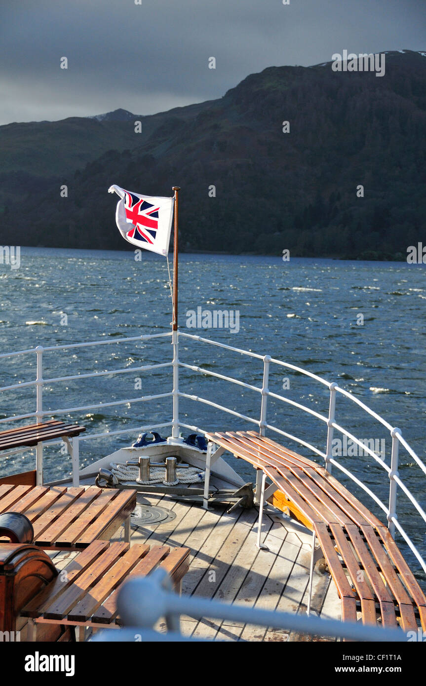 Flag flying on bow of ferry crossing Ullswater Lake in winter from ...