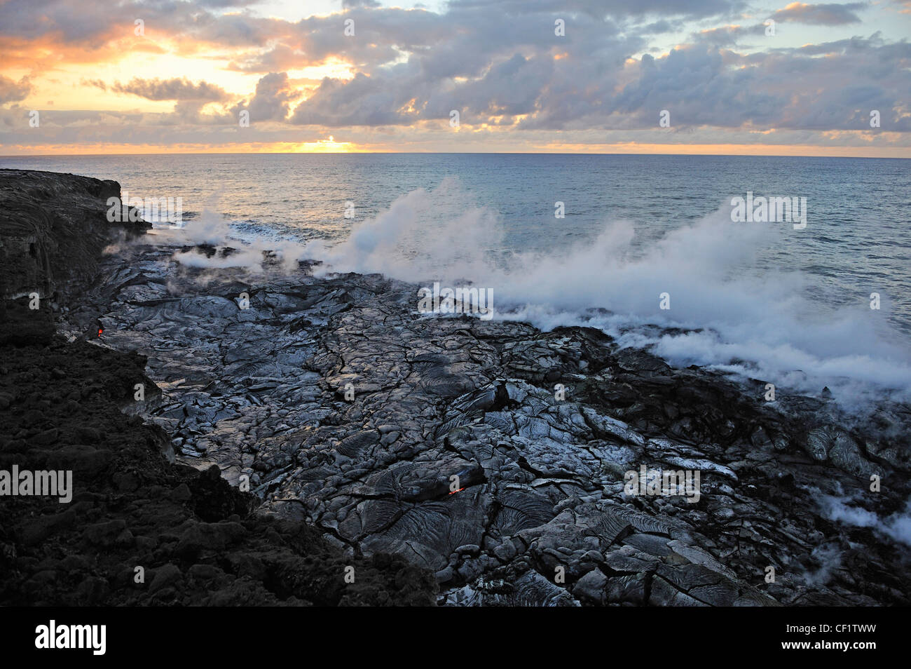 Cooled pahoehoe lava and steam rising off flowing lava into ocean ...