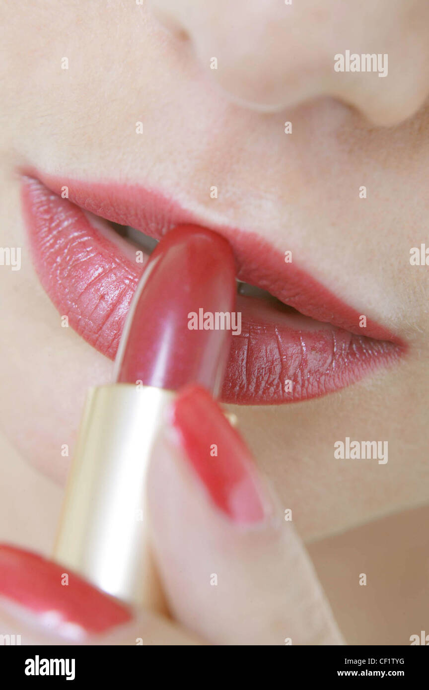 Cropped image of female lips with red lipstick being applied red finger ...