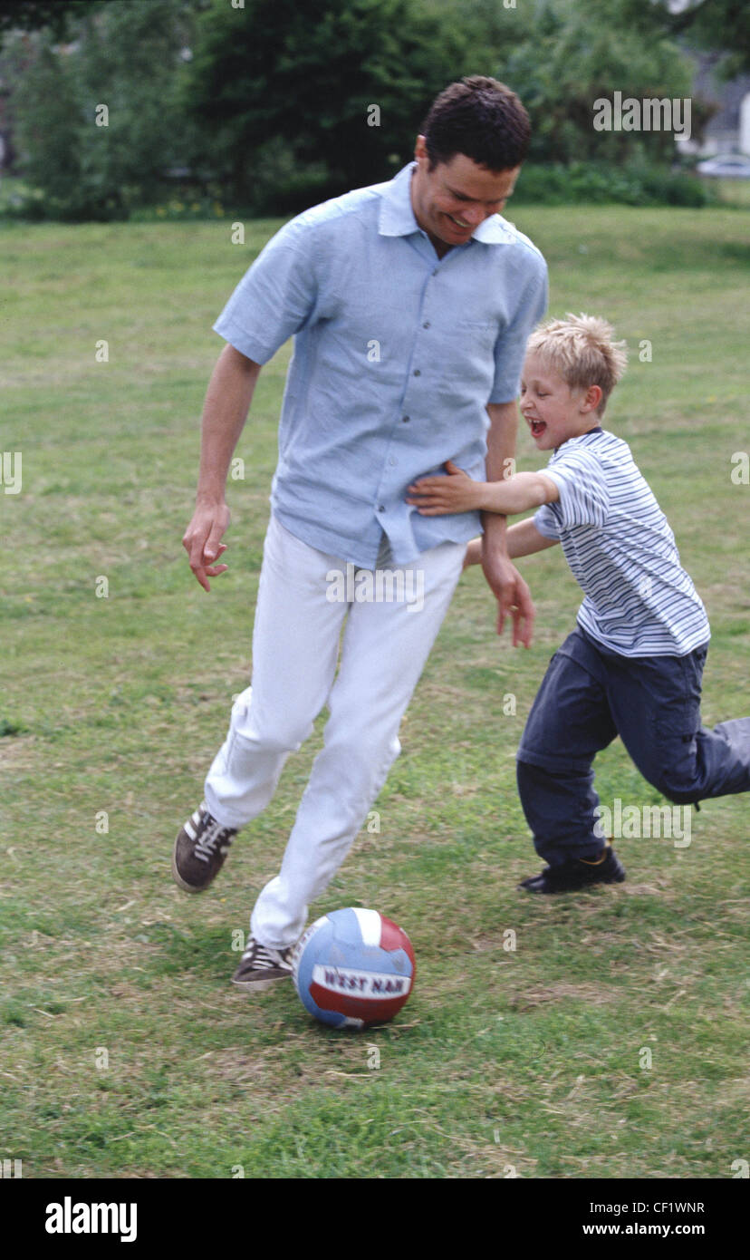 Father with short brown hair about to kick football male child blonde ...