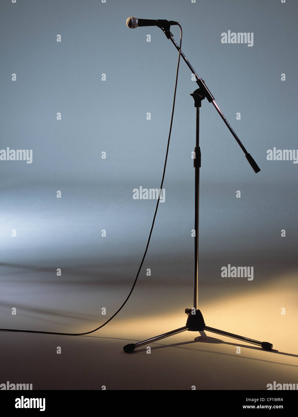 Microphone on stand in studio lit with warm spotlight, grey background ...