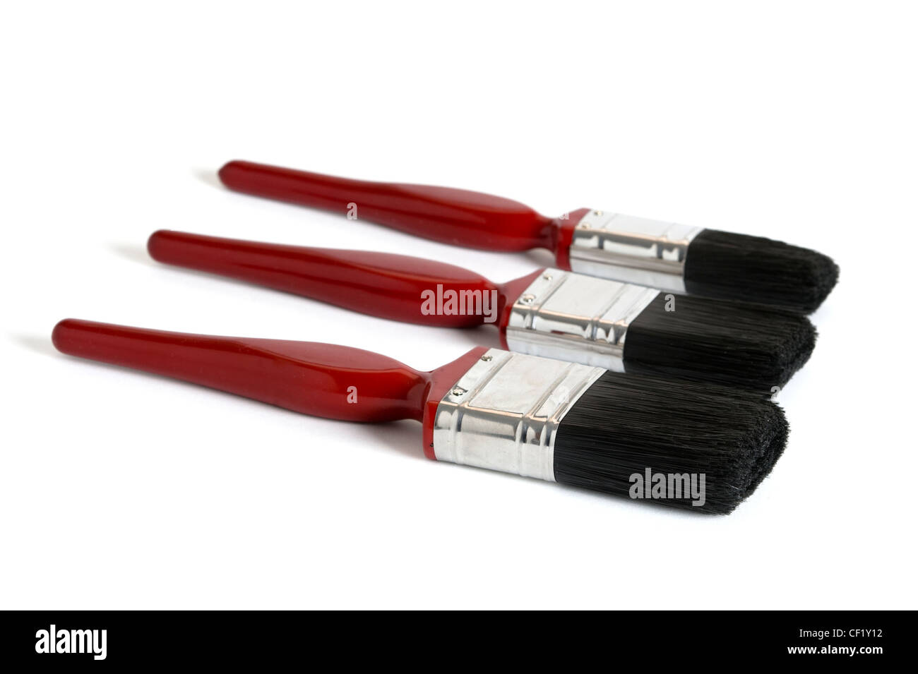 three red paintbrushes of different sizes isolated on a white ...