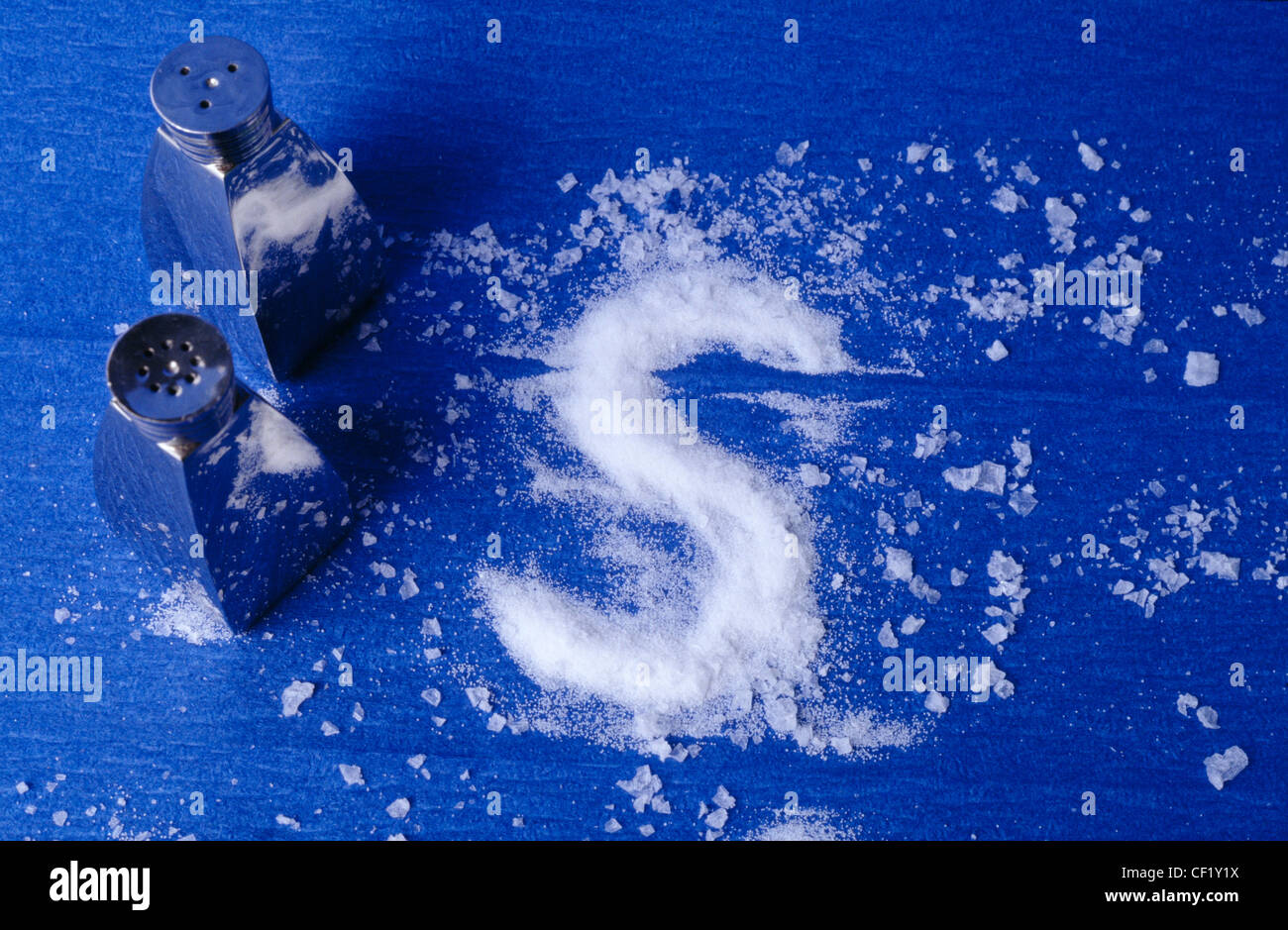 Two chrome metal pepper and salt shakers reflecting blue surface spilt ...