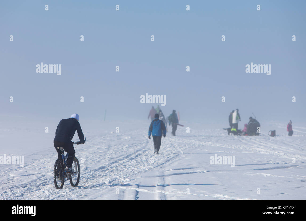 Group of people ice fishing , biking and walking on foggy sea ice at ...