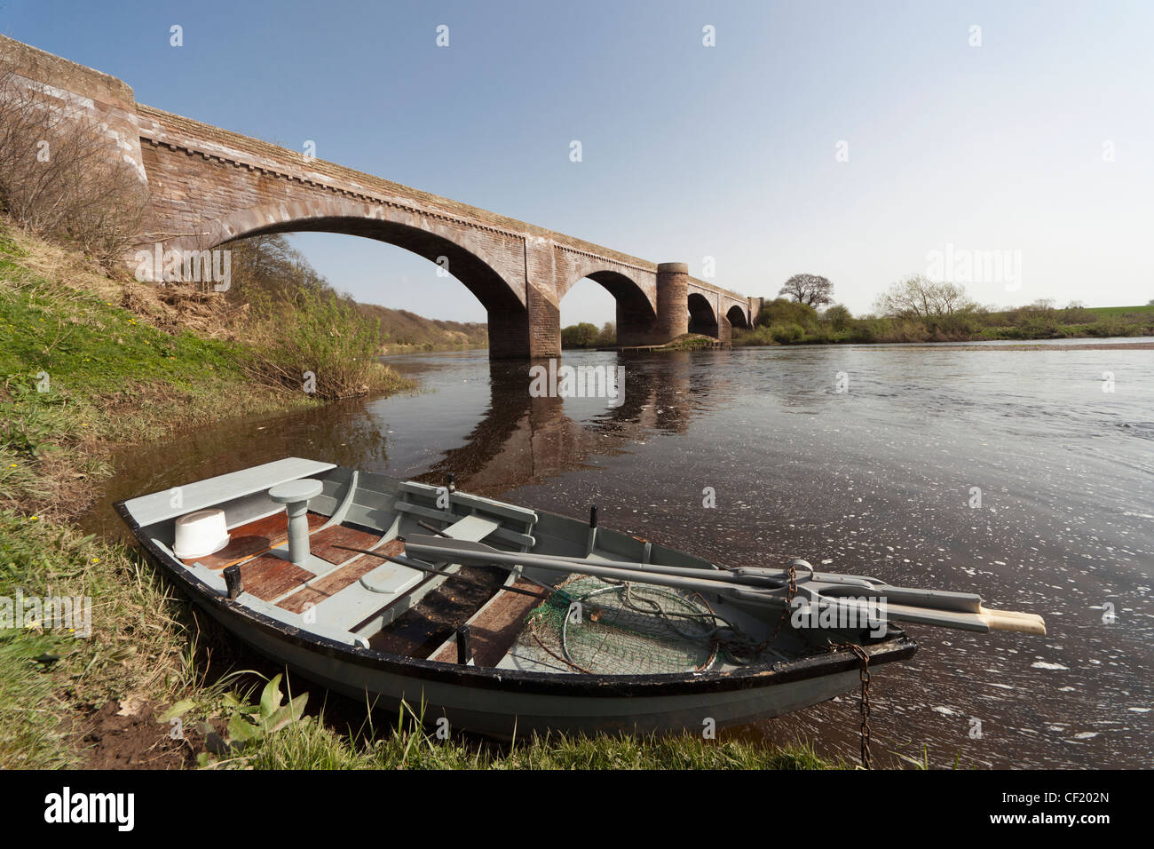 A Boat Along The Shoreline Beside A Bridge In River Tweed; Scottish ...