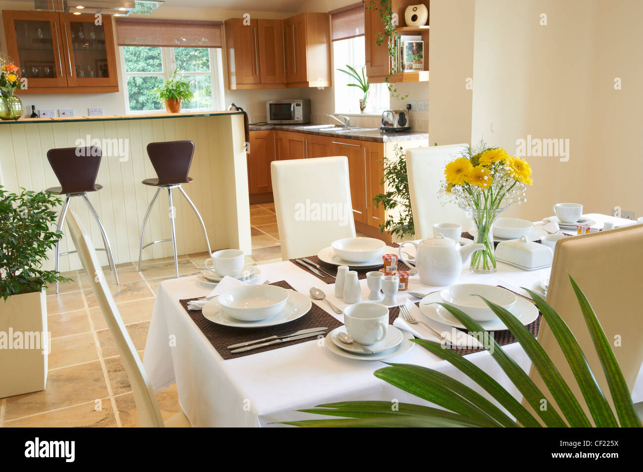 A modern kitchen/diner with a table laid ready for breakfast, with ...