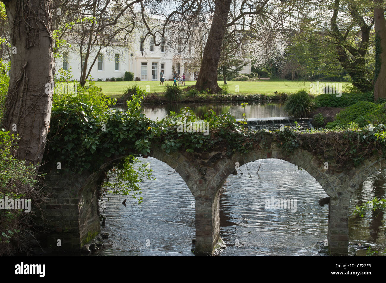 Arch bridge over stream by country house Stock Photo - Alamy