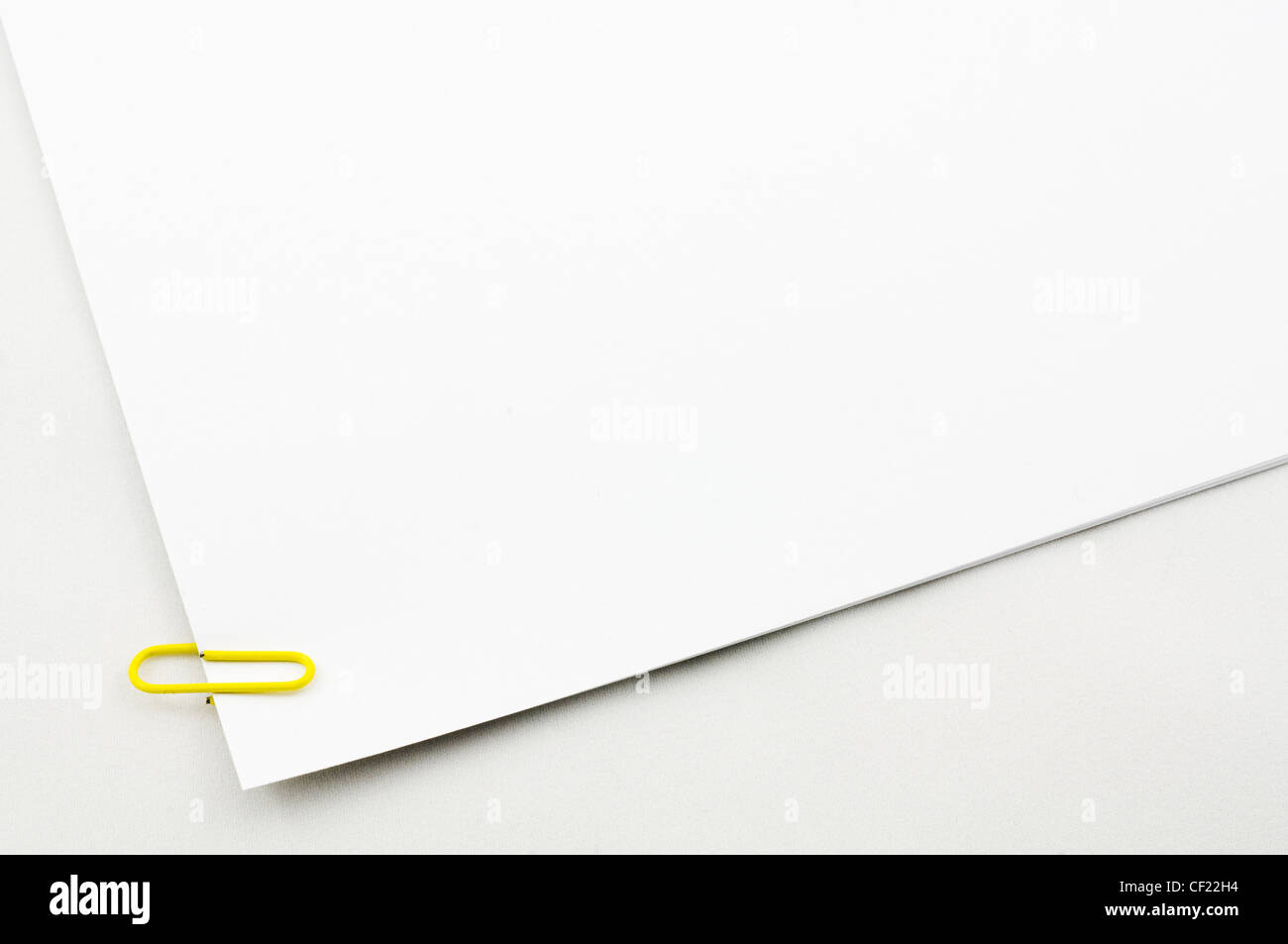 Closeup of a yellow plastic paper clip on empty paper sheets Stock ...