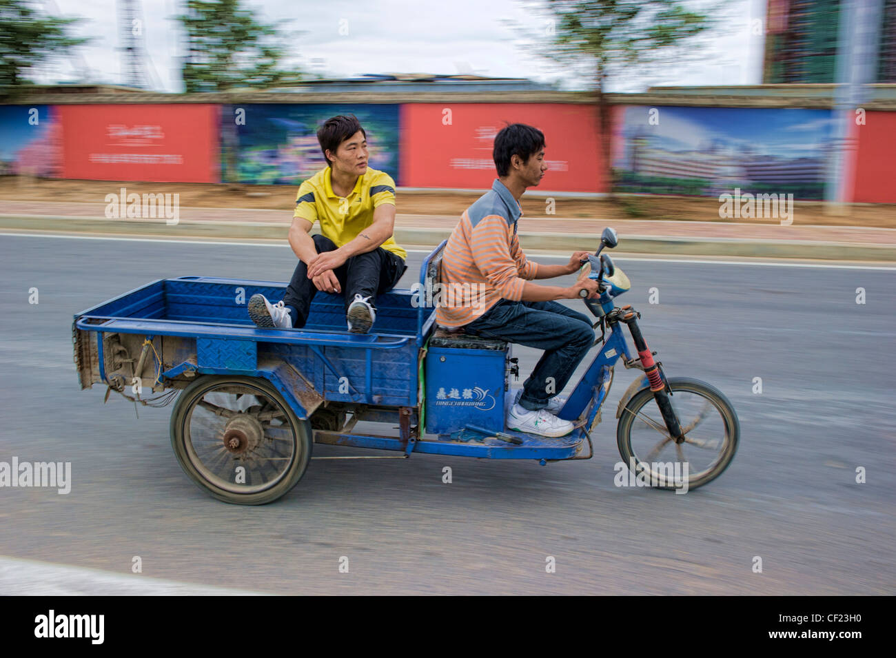 Two young Chinese men riding a three wheeled truck Stock Photo - Alamy