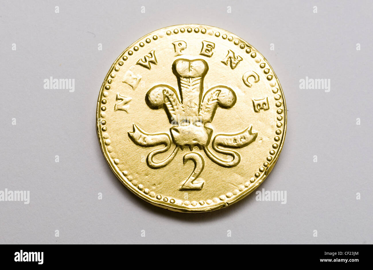 Close up of a single gold chocolate pence coin, photographed on plain ...